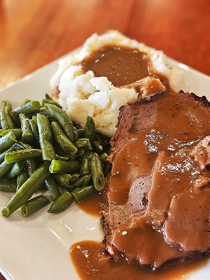 A plate that understands the importance of gravy lakes touching every island of food. Those green beans are just pretending to be healthy&mdash;they've been partying with pork all day.