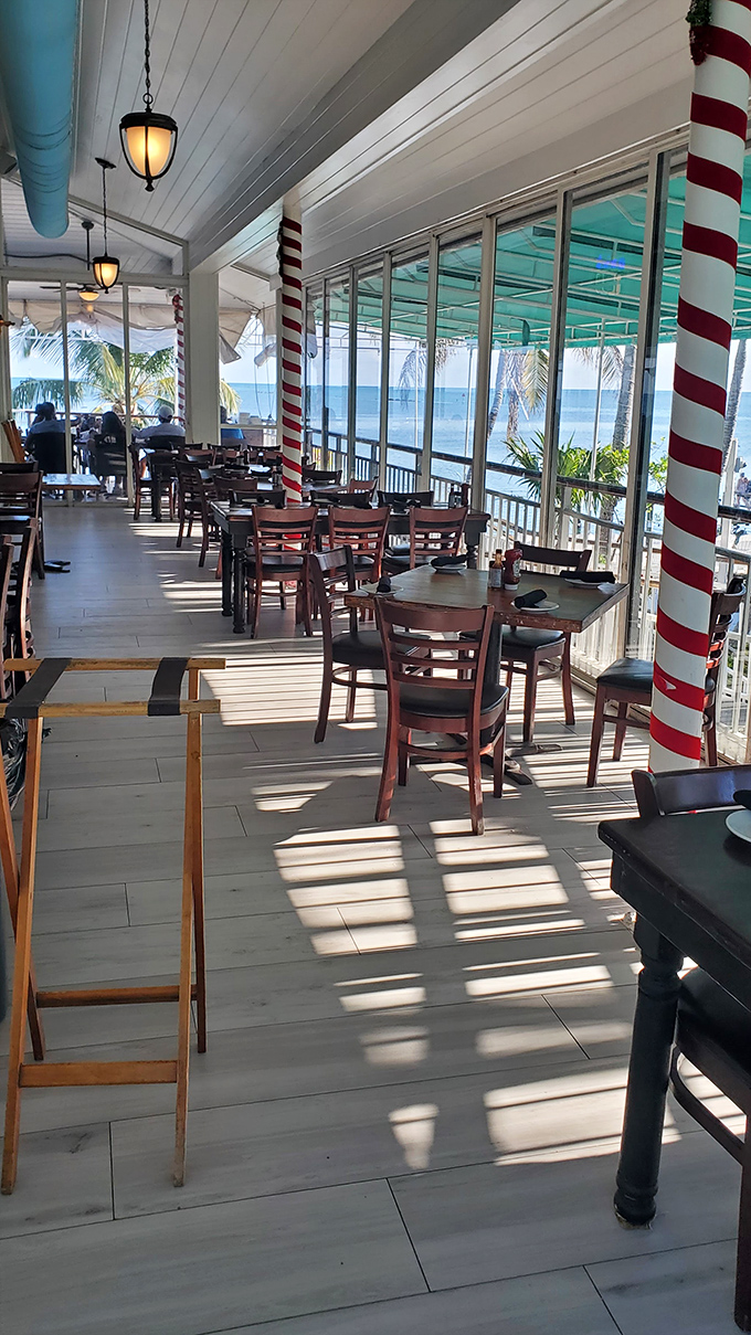 Candy-striped columns frame postcard-perfect views. The dining room proves that sometimes the best seasoning is simply watching the waves roll in between bites.