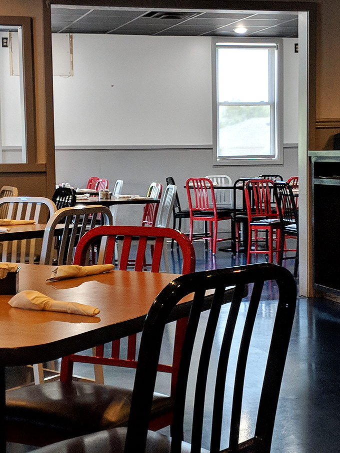 Red chairs pop against neutral walls, creating that classic diner feel where conversations flow as easily as the coffee refills.