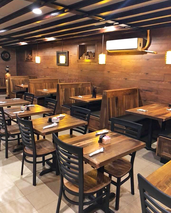 The wooden booth section offers a more intimate dining experience, where warm lighting and natural materials create a sanctuary for serious eating.