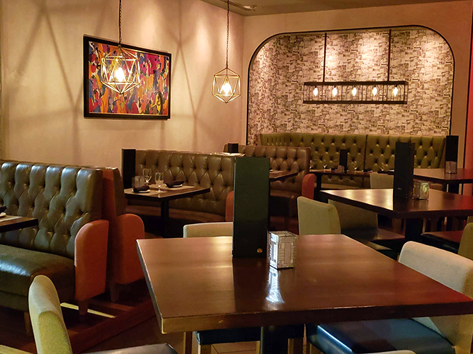 Tufted booths and geometric lighting create intimate dining spaces that say, "Stay awhile, the outside world can wait."