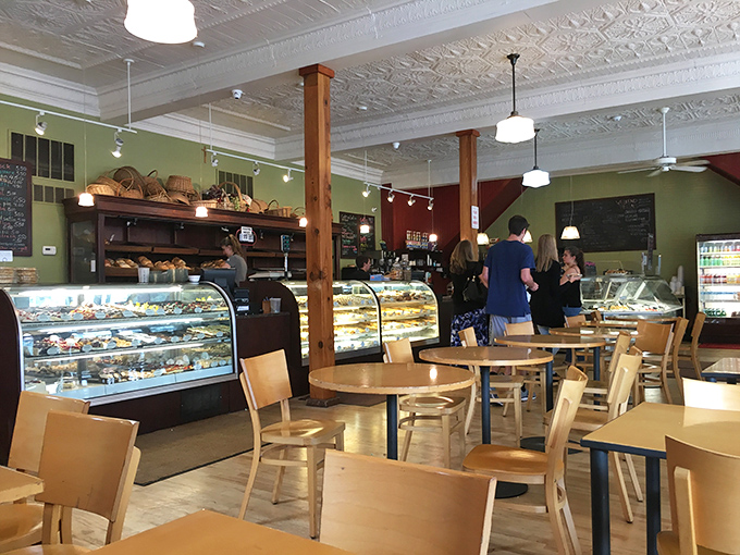 Wooden pillars frame the bakery's treasures like a museum of edible art. The bread shelves above offer carb-lovers a gallery of crusty masterpieces.