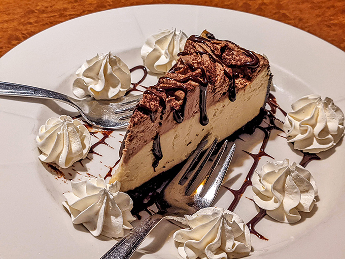 This isn't just cheesecake&mdash;it's a chocolate-drizzled masterpiece surrounded by whipped cream sentinels standing guard until your fork arrives. 