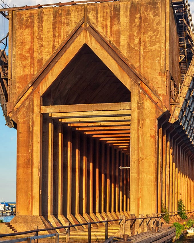 Sunlight transforms the historic ore dock into a golden passageway, each massive timber column creating a hypnotic rhythm of light and shadow.