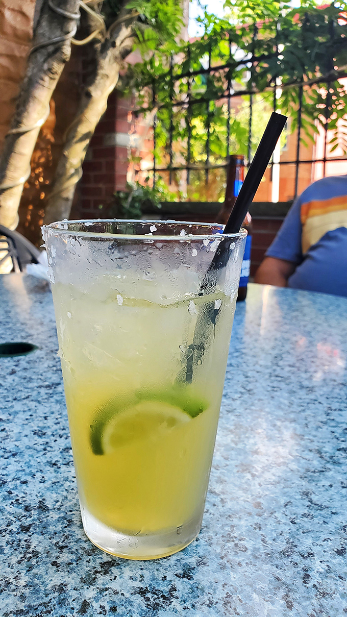 A margarita that looks like liquid sunshine, served in the outdoor patio. The condensation on the glass practically whispers "summer afternoon."
