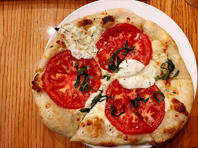 Pizza perfection in its simplest form—where fresh tomatoes and basil prove that sometimes less is magnificently more.