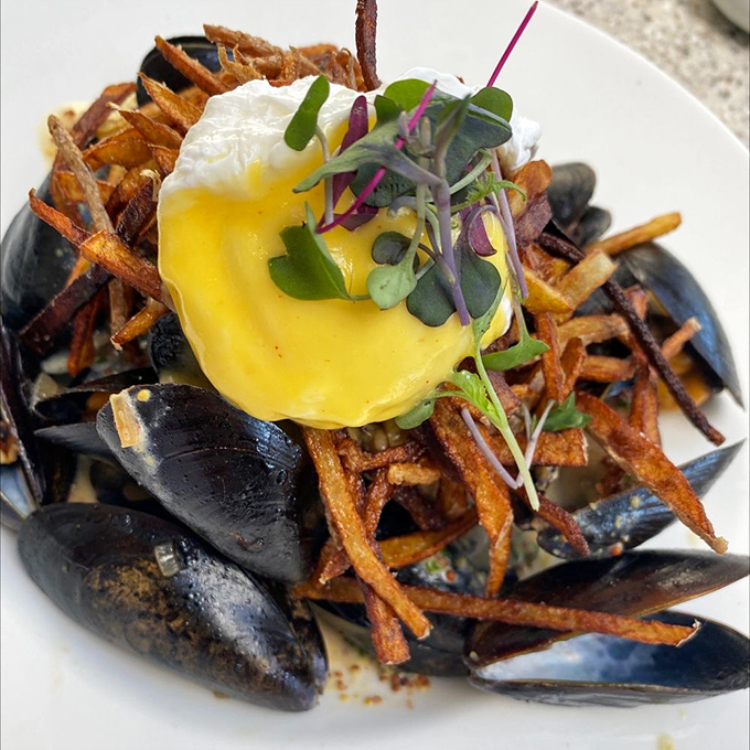 Mussels that look like they're having their own little party, with crispy fries and a poached egg VIP guest.