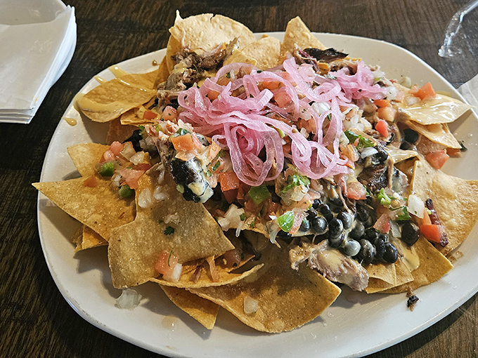 Nachos that refuse to be an afterthought—loaded with smoked meat, fresh toppings, and those magnificent pink pickled onions that brighten everything they touch.