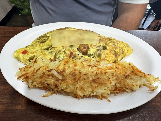An omelet that's seen more fillings than a dentist's office, paired with hash browns so crispy they practically sing. Breakfast perfection on a plate.