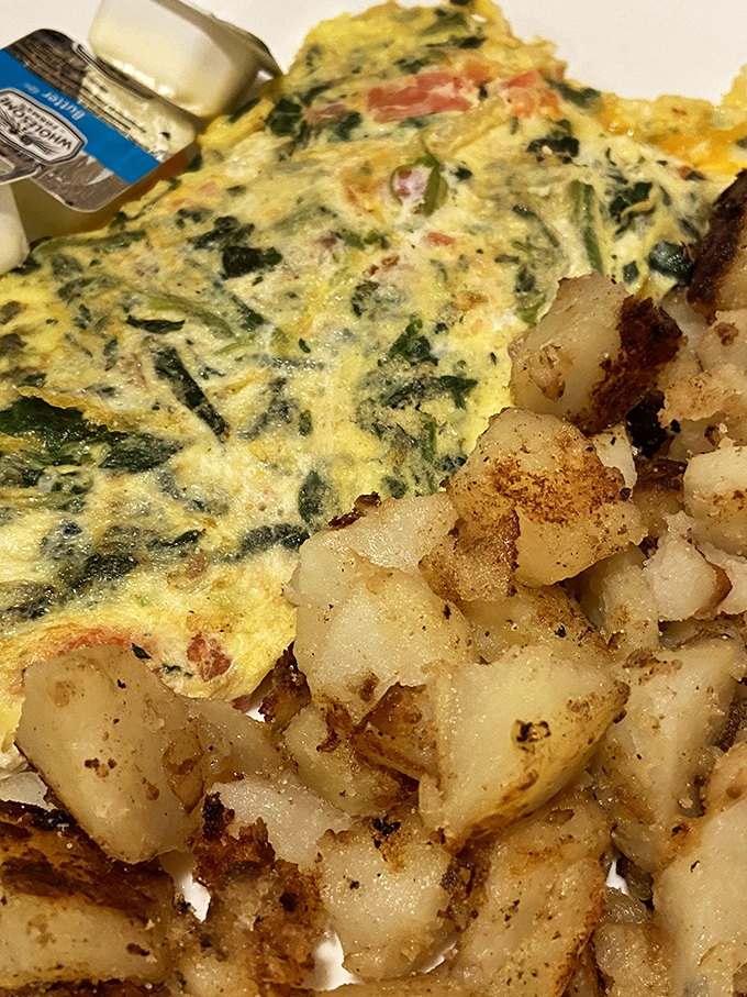 An omelet bursting with fresh vegetables alongside perfectly seasoned home fries. Proof that breakfast can be both virtuous and indulgent.
