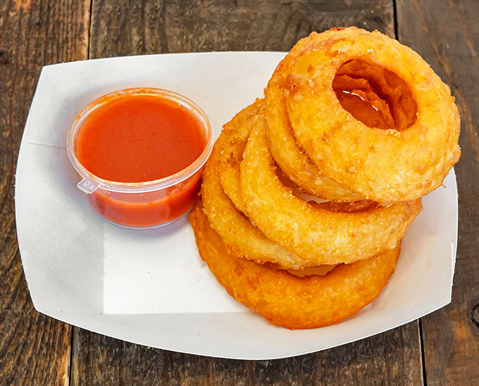 Onion rings stacked like edible jewelry, with a sauce that could make cardboard taste good. Crispy, sweet, and utterly irresistible.
