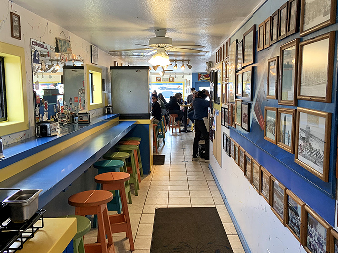 The narrow hallway lined with framed memories and colorful stools feels like walking through a beloved family album of coastal California dining history.