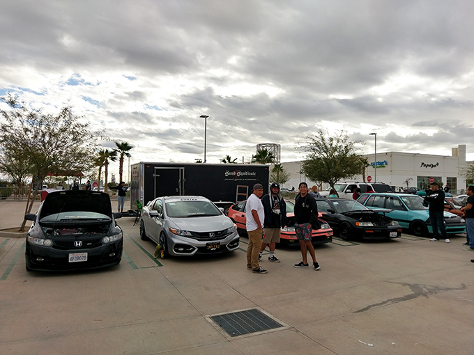 The parking lot: where car enthusiasts gather to admire engines while their passengers hunt for deals inside&mdash;a symbiotic relationship as old as retail itself.