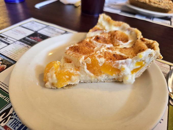This slice of peach pie isn't just dessert; it's edible sunshine with a golden crust that shatters perfectly under your fork.