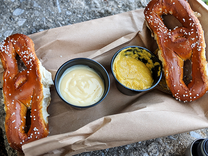 Two pretzels and dipping sauces on brown paper&mdash;street food elevated to an art form without losing its unpretentious soul. 