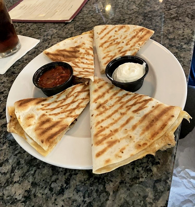 These quesadillas have achieved that perfect golden-brown exterior that makes you want to frame them before devouring them. The accompanying salsa and sour cream stand ready for duty.