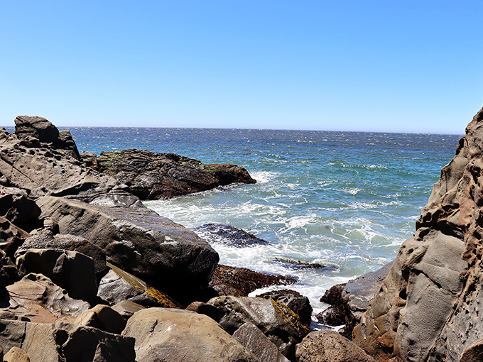 Jagged rock formations create perfect frames for watching the endless dance between waves and shore.