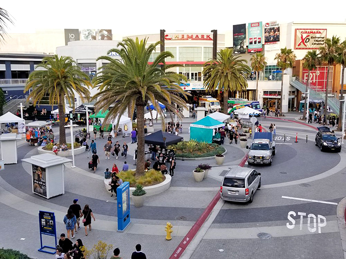 Palm trees frame busy shoppers as they navigate this outdoor retail oasis under California's endless blue sky.