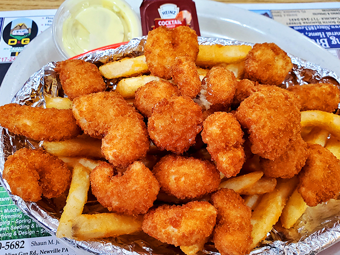 Golden shrimp nuggets nestled with fries like tiny treasures from the sea, served with cocktail sauce for the perfect dip.
