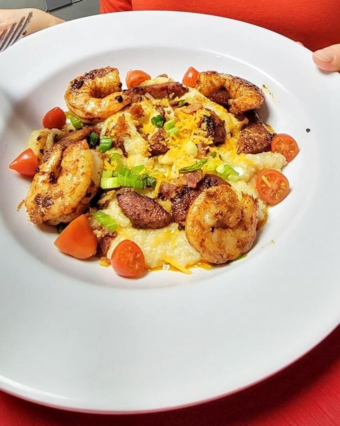 Southern comfort meets coastal flair in this masterpiece of creamy grits topped with perfectly seasoned shrimp, sausage, and fresh tomatoes.