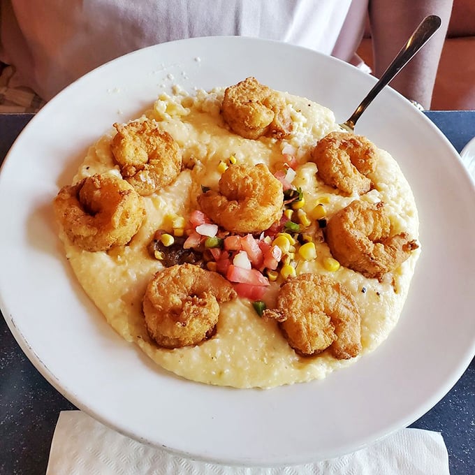 These shrimp and grits elevate a Southern classic to art form status—golden crustaceans resting on a canvas of creamy cornmeal perfection.