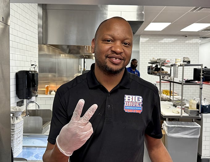 Behind every great cheesesteak is a team that understands the sacred bond between bread, meat, and cheese. The peace sign says it all&mdash;sandwich harmony achieved.