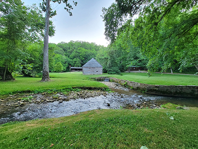 Summer's lush greenery frames a pioneer cabin and stream, creating a scene so idyllic it belongs on a vintage Indiana postcard.
