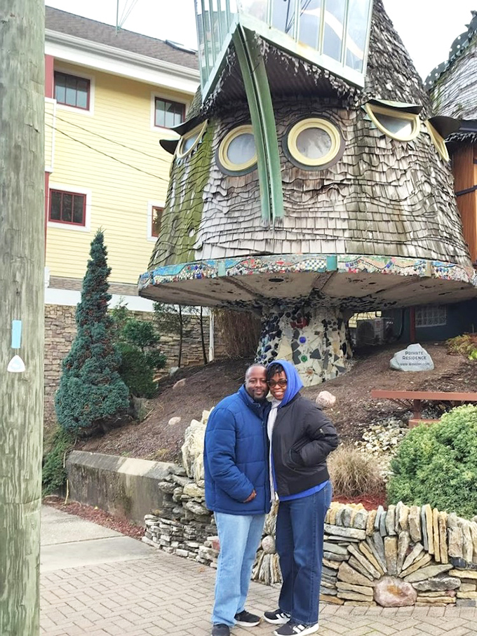Visitors pose beneath the distinctive cap of the Mushroom House, collecting photographic evidence that yes, this place actually exists.