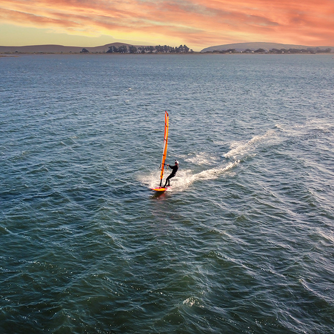 Some people Netflix and chill. Others windsurf at sunset against a backdrop that makes your phone wallpaper look like amateur hour.