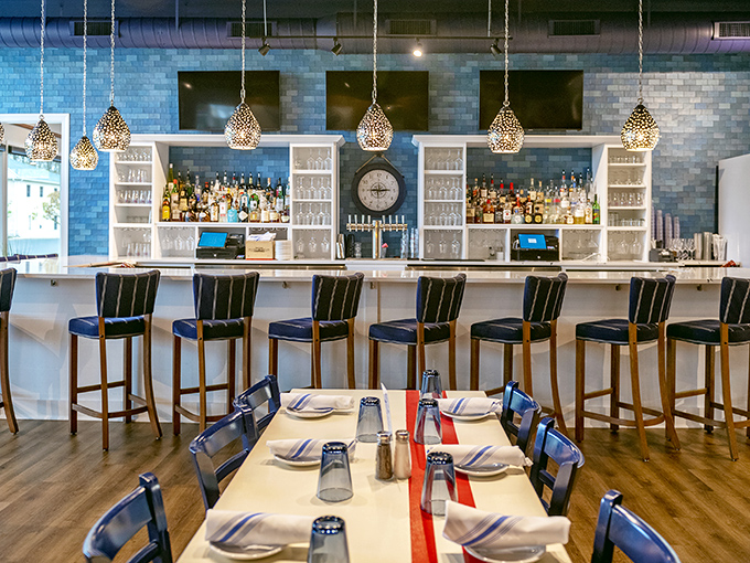 The bar area combines coastal blues with elegant lighting, creating the perfect spot to sip something cold while debating which seafood treasure to order next.