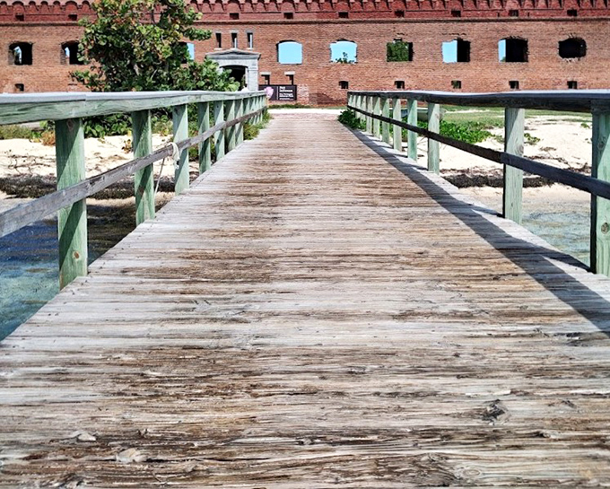 The wooden pathway to paradise leads visitors across shallow waters to Fort Jefferson's entrance, like a humble red carpet for history buffs.