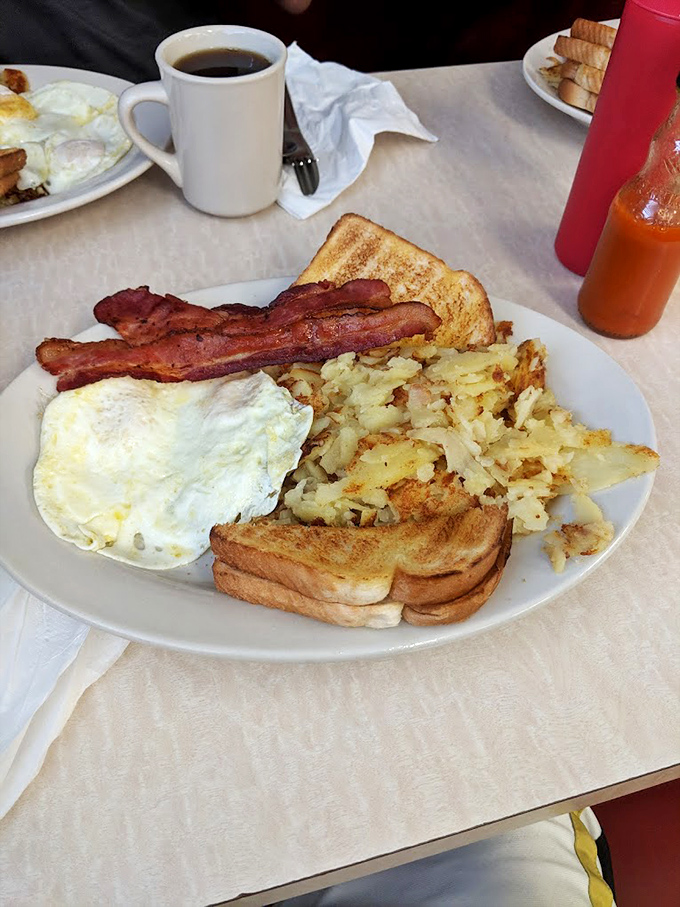 The breakfast trinity: crispy bacon, eggs with intact yolks, and hash browns with the perfect crisp-to-tender ratio. Diner nirvana achieved.