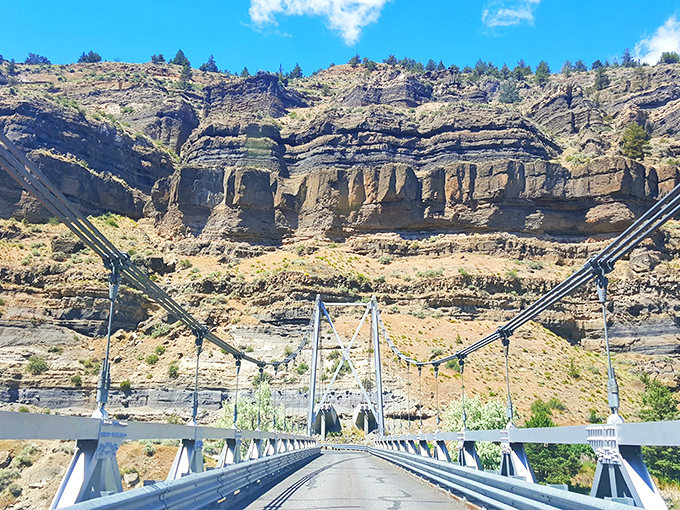 The bridge spans canyon walls like a scene from an old Western, connecting two worlds above the pristine waters below.