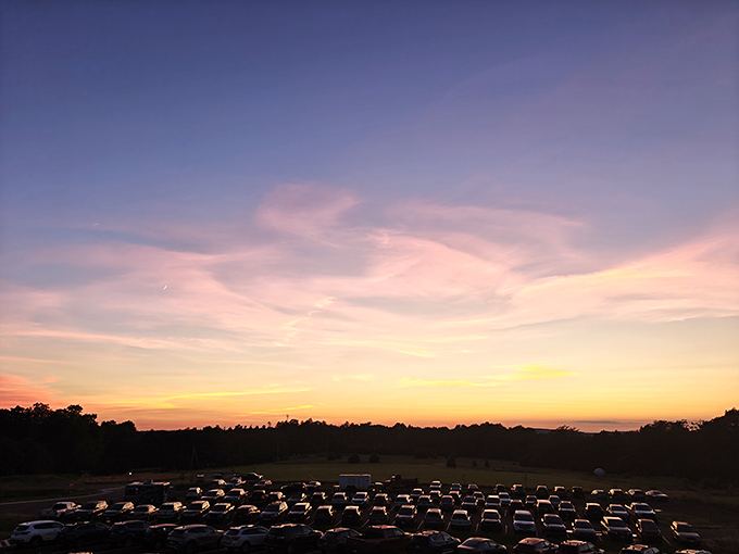 The parking area fills with astronomy enthusiasts as darkness approaches. Each car carries people eager to trade city lights for starlight.