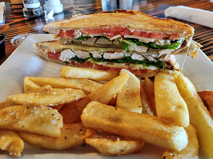 This sandwich means business&mdash;layers of chicken, fresh vegetables, and what looks like melty cheese, escorted by golden fries that demand equal attention.