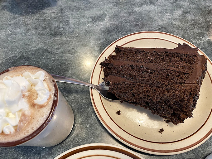 The chocolate cake and whipped-cream-topped coffee create the kind of dessert moment that makes you consider cake as a legitimate breakfast option.