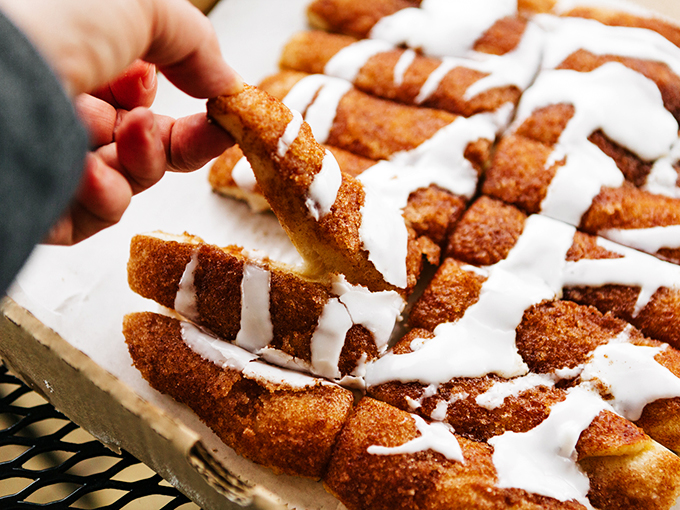 Cinnamon sticks drizzled with icing &ndash; dessert disguised as bread, proving that the best endings are sweet, warm, and slightly messy.