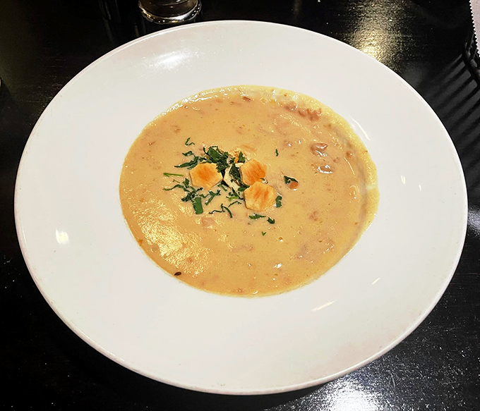 Creamy clam chowder arrives steaming hot with visible chunks of seafood, proving that some classics never need updating or unnecessary tweaking.