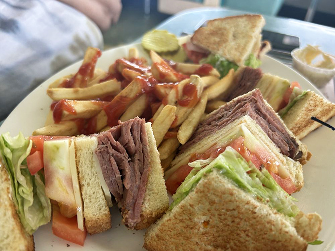 The club sandwich—three layers of architectural brilliance. Like the Empire State Building of lunch, it towers with purpose and demands respect.