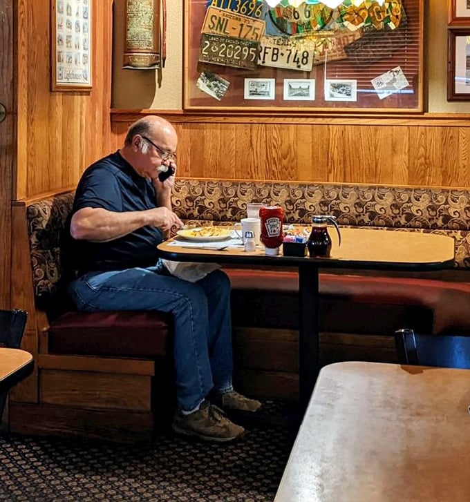 The quintessential diner experience: a regular enjoying his breakfast in a wood-paneled booth beneath vintage license plates &ndash; Norman Rockwell would approve.