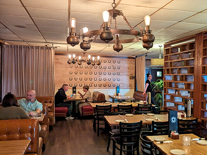 The dining room buzzes with conversation as vintage-style chandeliers cast a warm glow over happy diners enjoying their steakhouse feast.