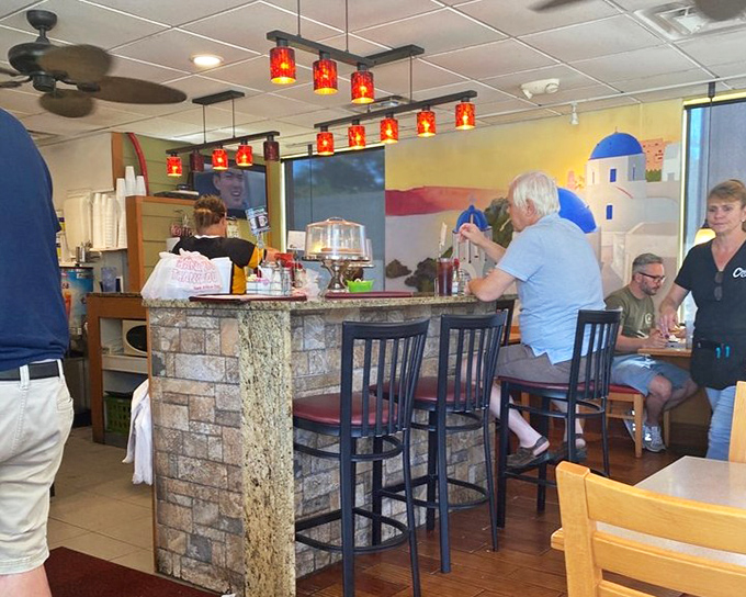 The counter seating offers front-row tickets to the breakfast show, where regulars exchange friendly banter while red pendant lights cast a warm glow.