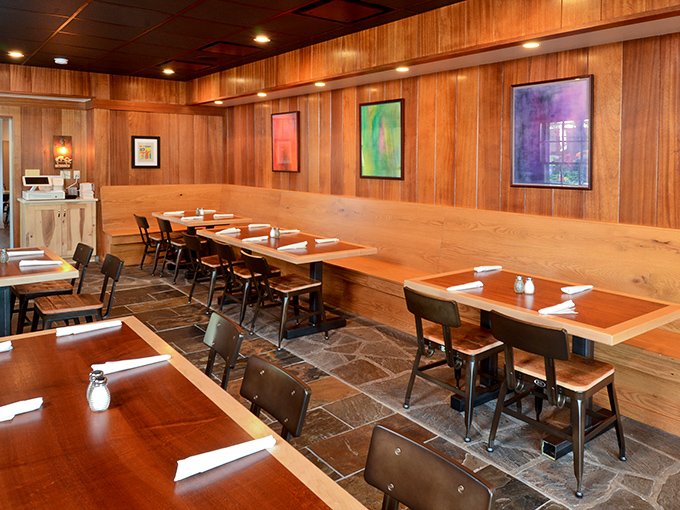 Wood paneling and colorful art create a dining room that feels like your coolest friend's cabin. Rustic without trying too hard.