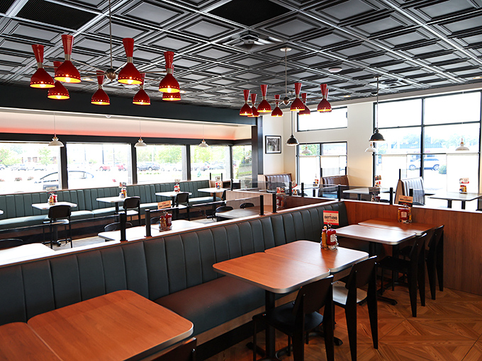 The dining room buzzes with conversation, where blue booths and pendant lights create the perfect casual dining atmosphere.