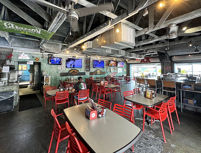 Industrial-chic meets beach casual with exposed ceiling, red chairs, and enough TVs to catch the game without missing a seafood moment.
