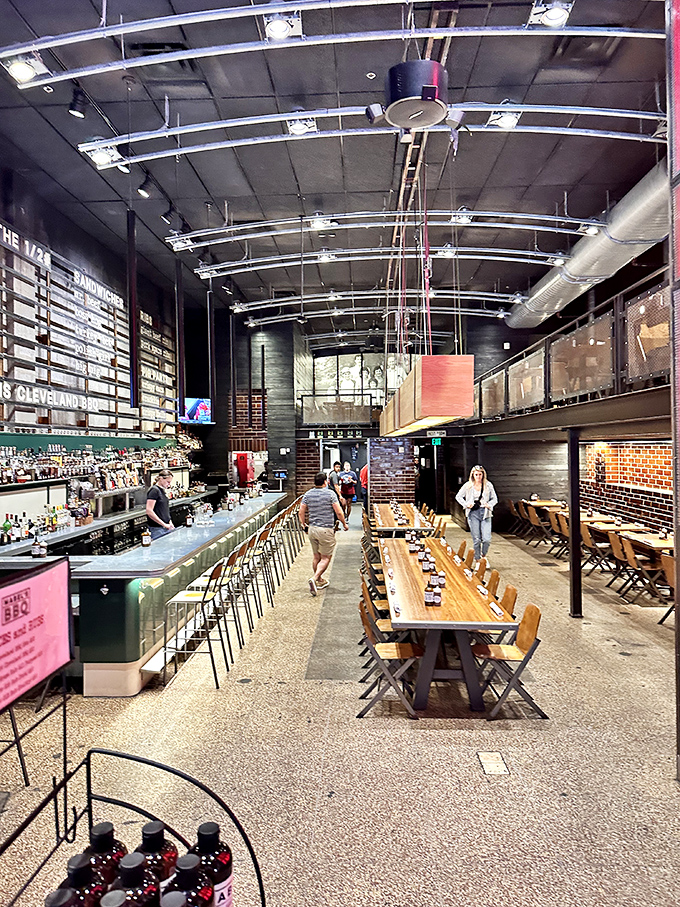 Long communal tables invite strangers to become friends over shared BBQ platters. The industrial ceiling keeps watch over meaty conversations.