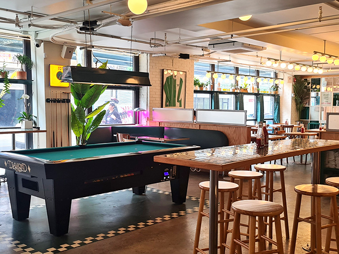 Not just food but fun&mdash;a pool table stands ready for between-bite entertainment in this plant-filled, light-drenched corner.