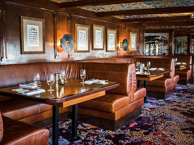 Rich leather booths and colorful carpets create intimate dining alcoves where conversations flow as smoothly as the Delaware outside.