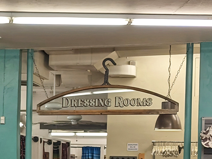 The dressing room sign hangs like a promise: behind these curtains, fashion transformations and "aha" moments await.