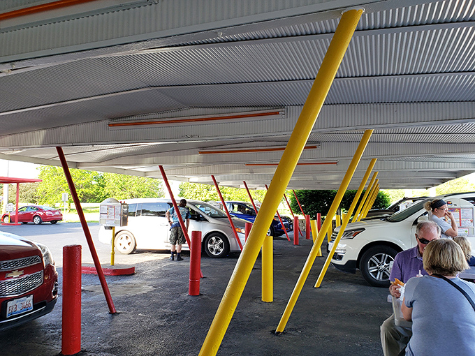 Under those angled yellow and red beams, strangers become neighbors united by the universal language of comfort food. Car hop service: social distancing before it was cool.